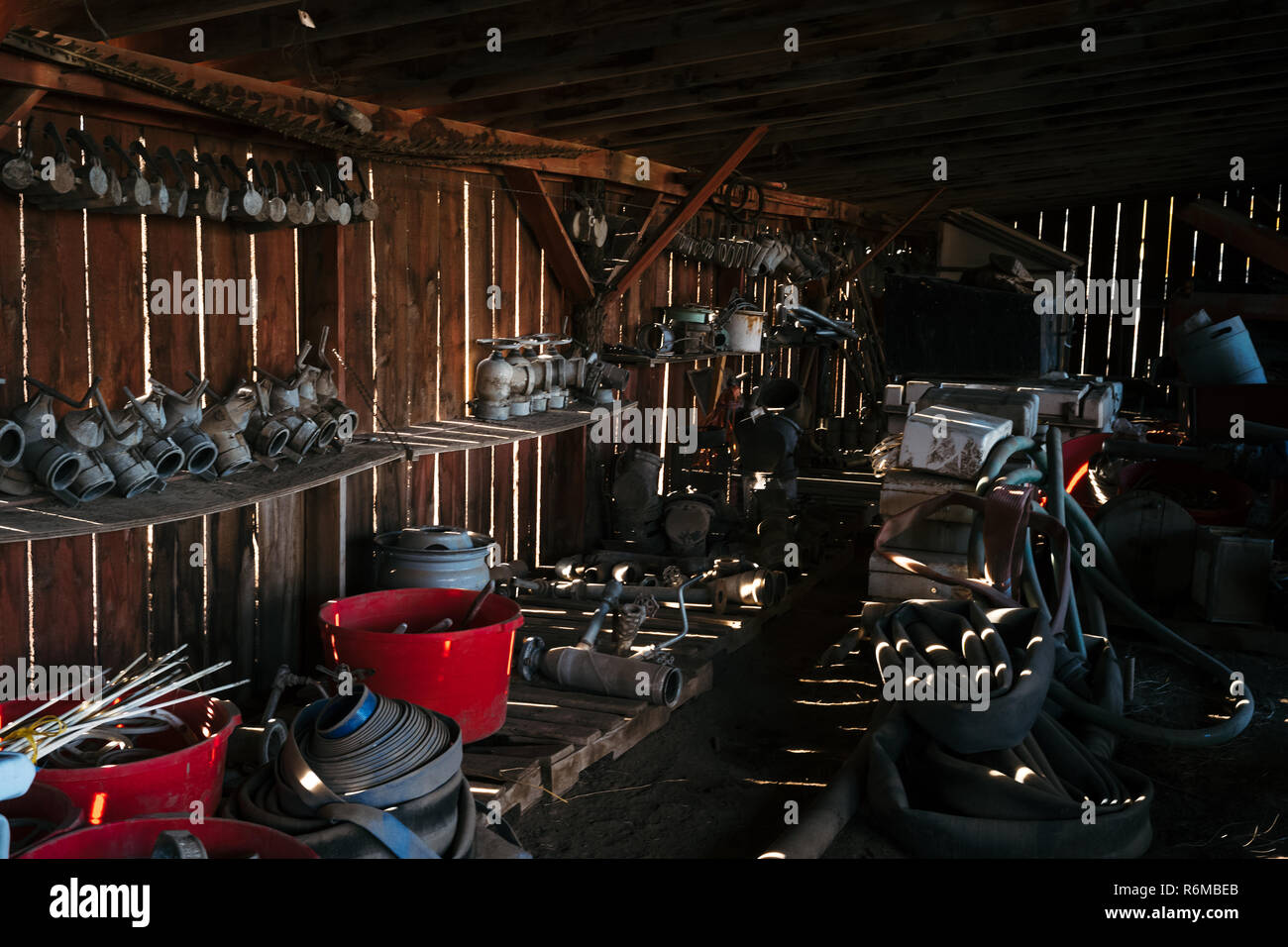 Spare parts organized on shelves in a rustic barn with sunlight coming ...