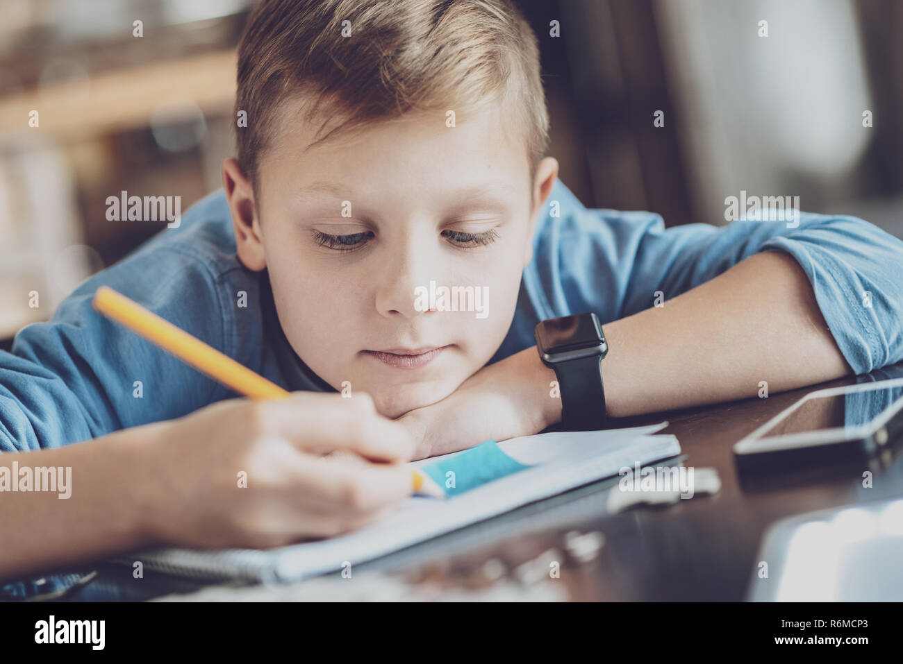Thoughtful blonde kid writing task Stock Photo - Alamy