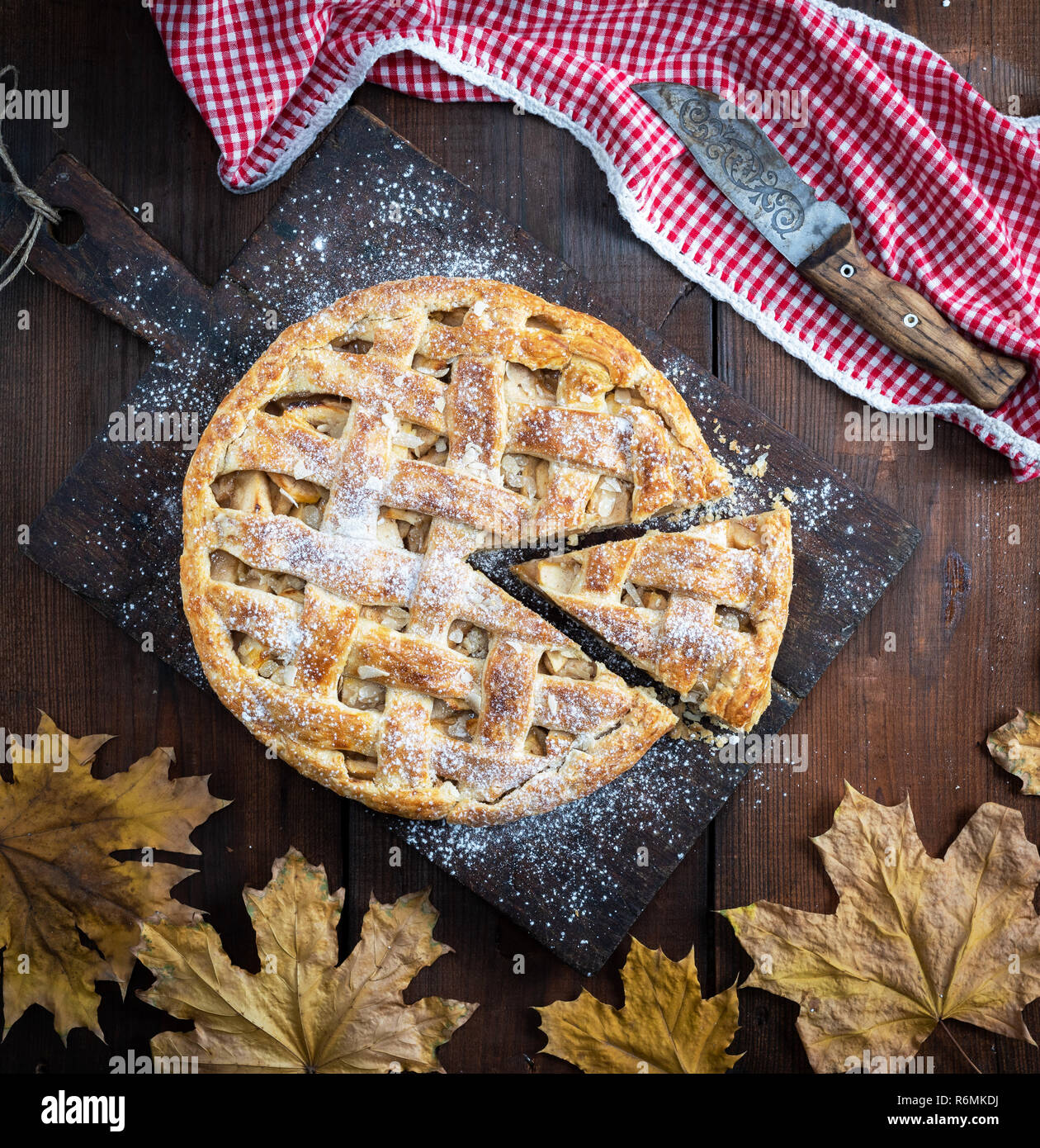 Baked whole round apple pie on a rectangular old brown board, wooden ...