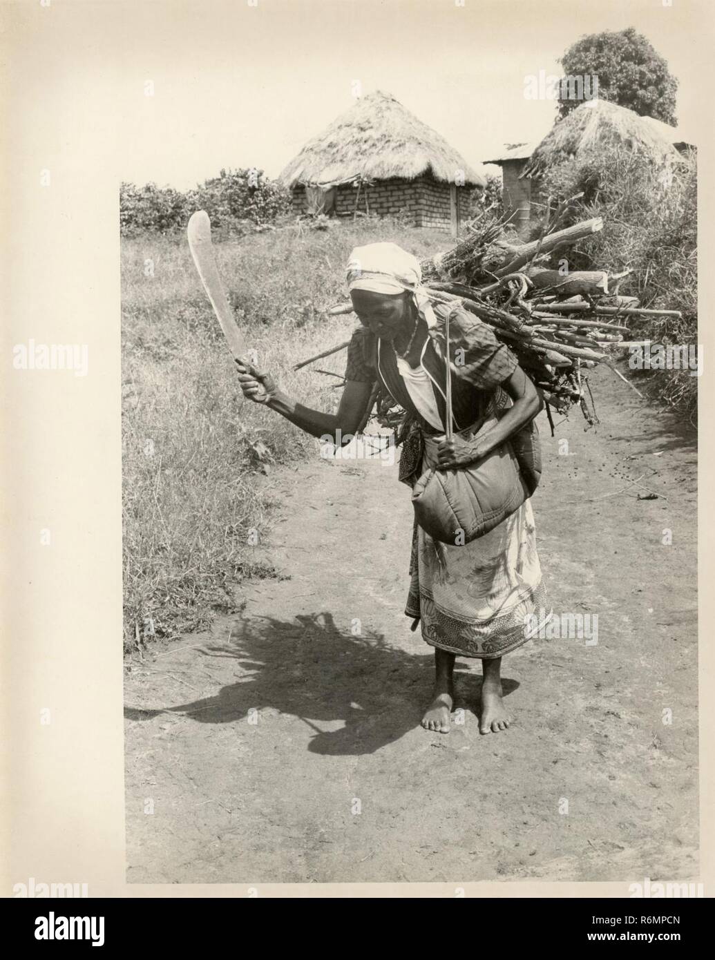An older woman carrying tree branches - holding a machete Stock Photo ...