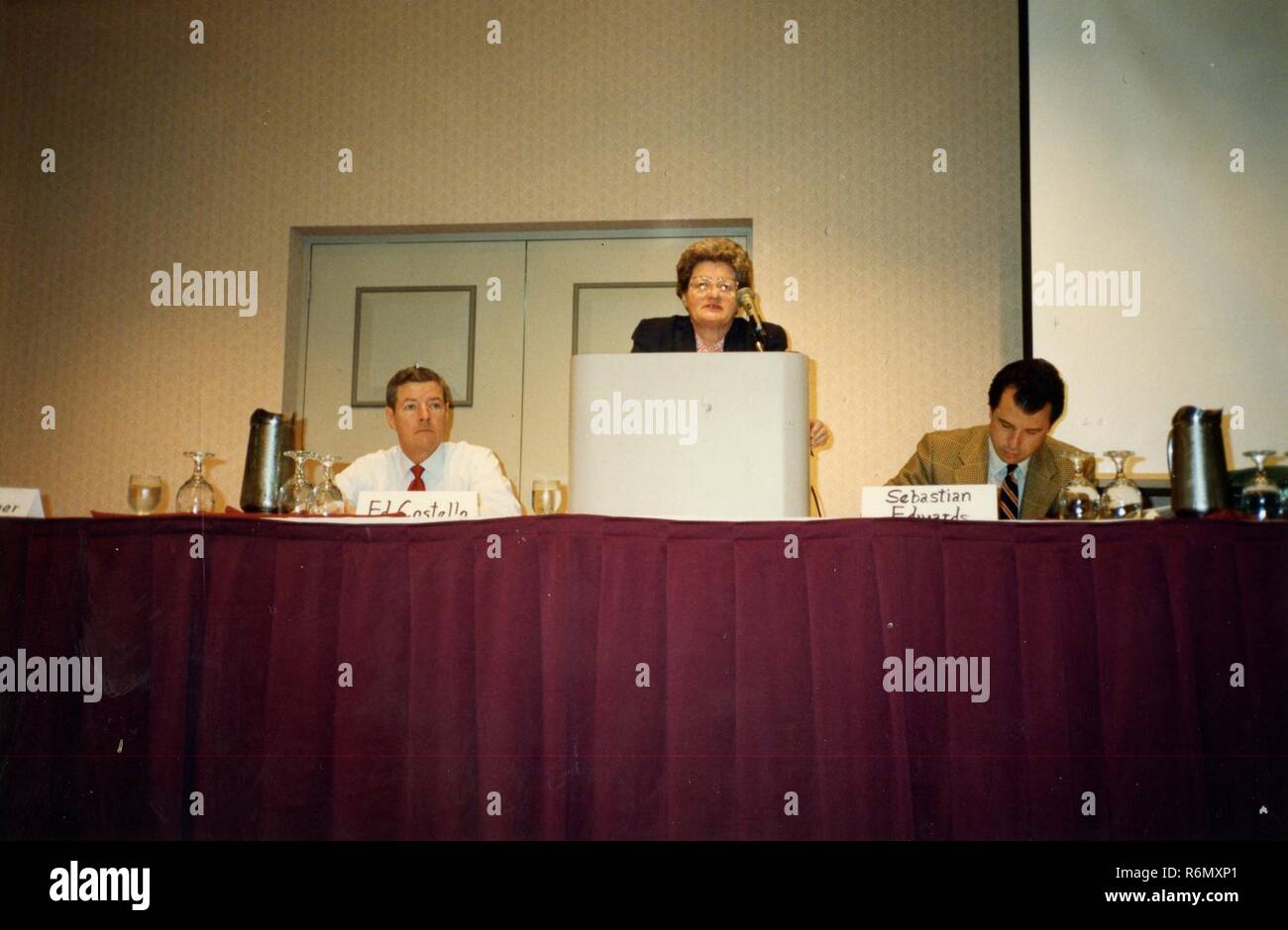 A WOMAN AT THE PODIUM WITH TWO MEN ON STAGE Stock Photo - Alamy