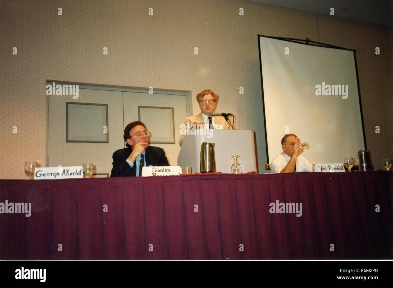 A MAN AT THE PODIUM WITH TWO OTHER MEN ON STAGE Stock Photo - Alamy