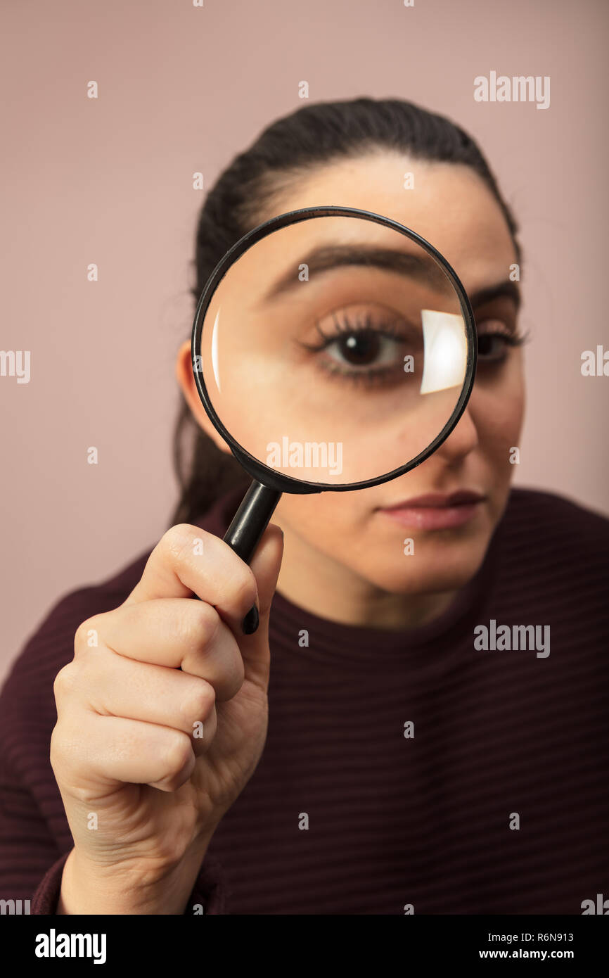 Woman looking through magnifying glass Stock Photo - Alamy