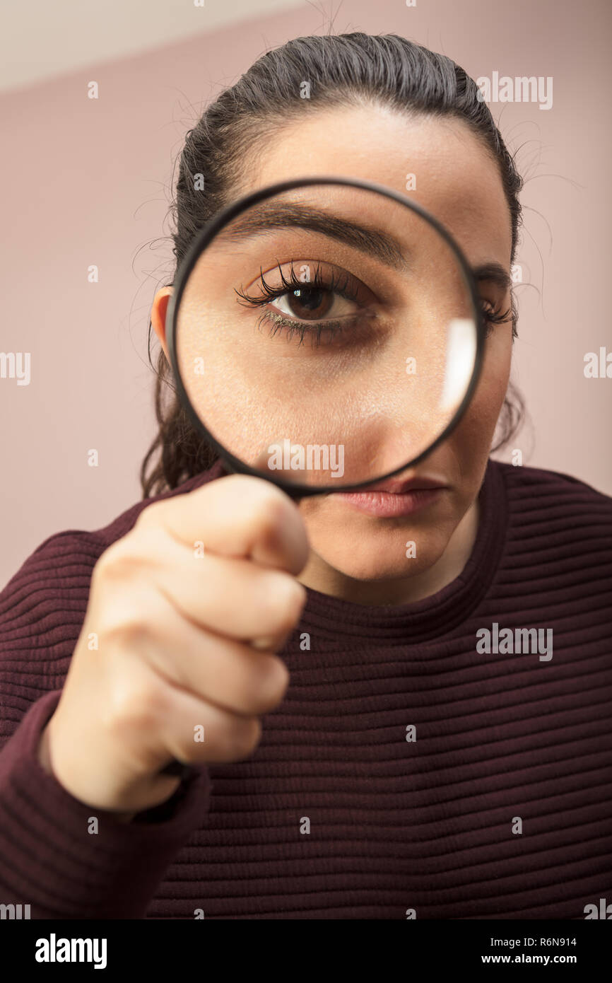 Woman looking through magnifying glass Stock Photo - Alamy