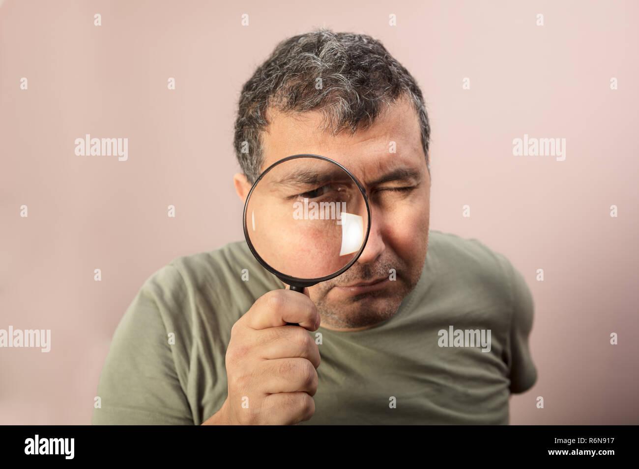 Man looking through magnifying glass Stock Photo - Alamy