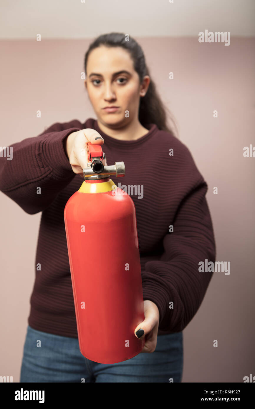 Young woman pointing a fire extinguisher forwards Stock Photo - Alamy