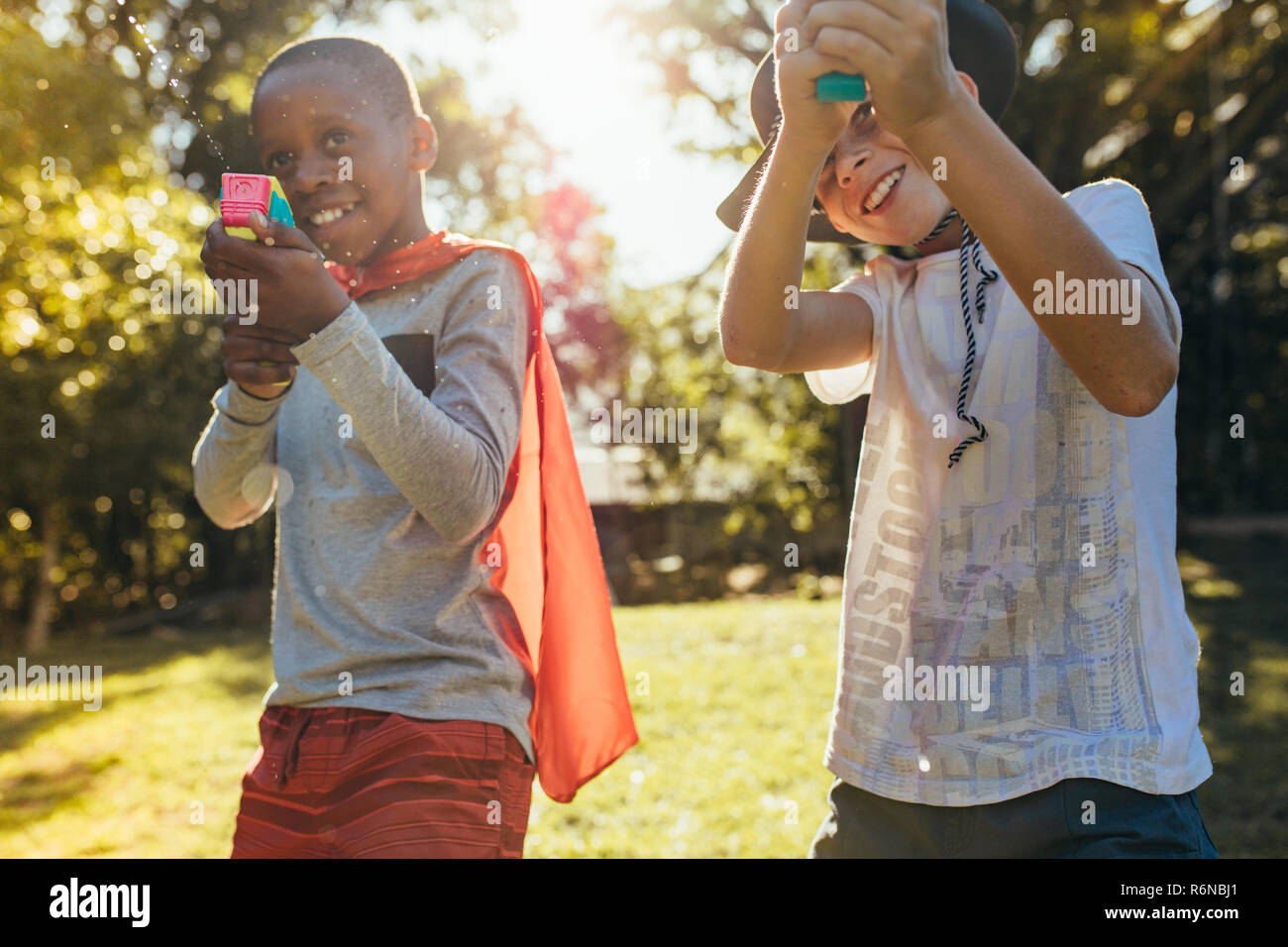 Kids playing with water guns outdoors. Little boys spraying water from ...