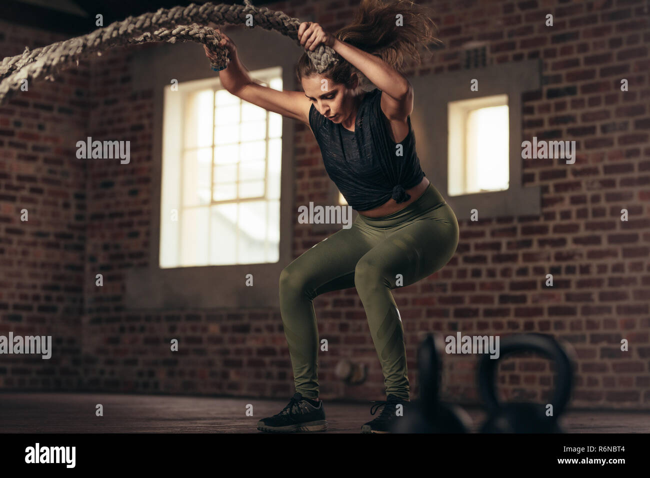 fitness woman using training ropes for exercise at gym. Athlete working ...