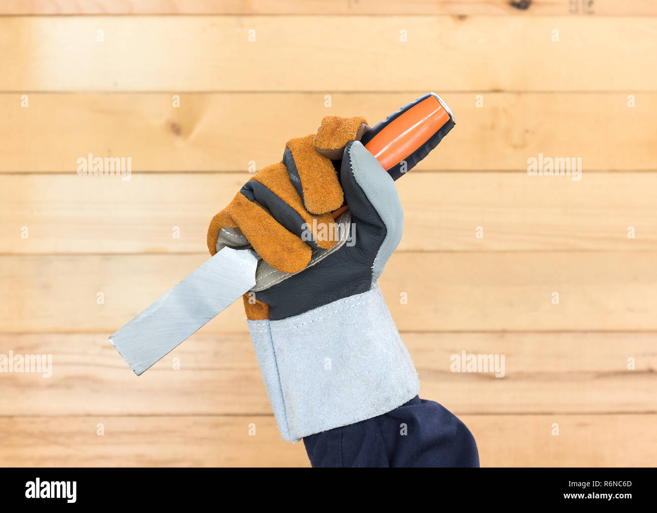 Hand in glove holding chisel Stock Photo - Alamy