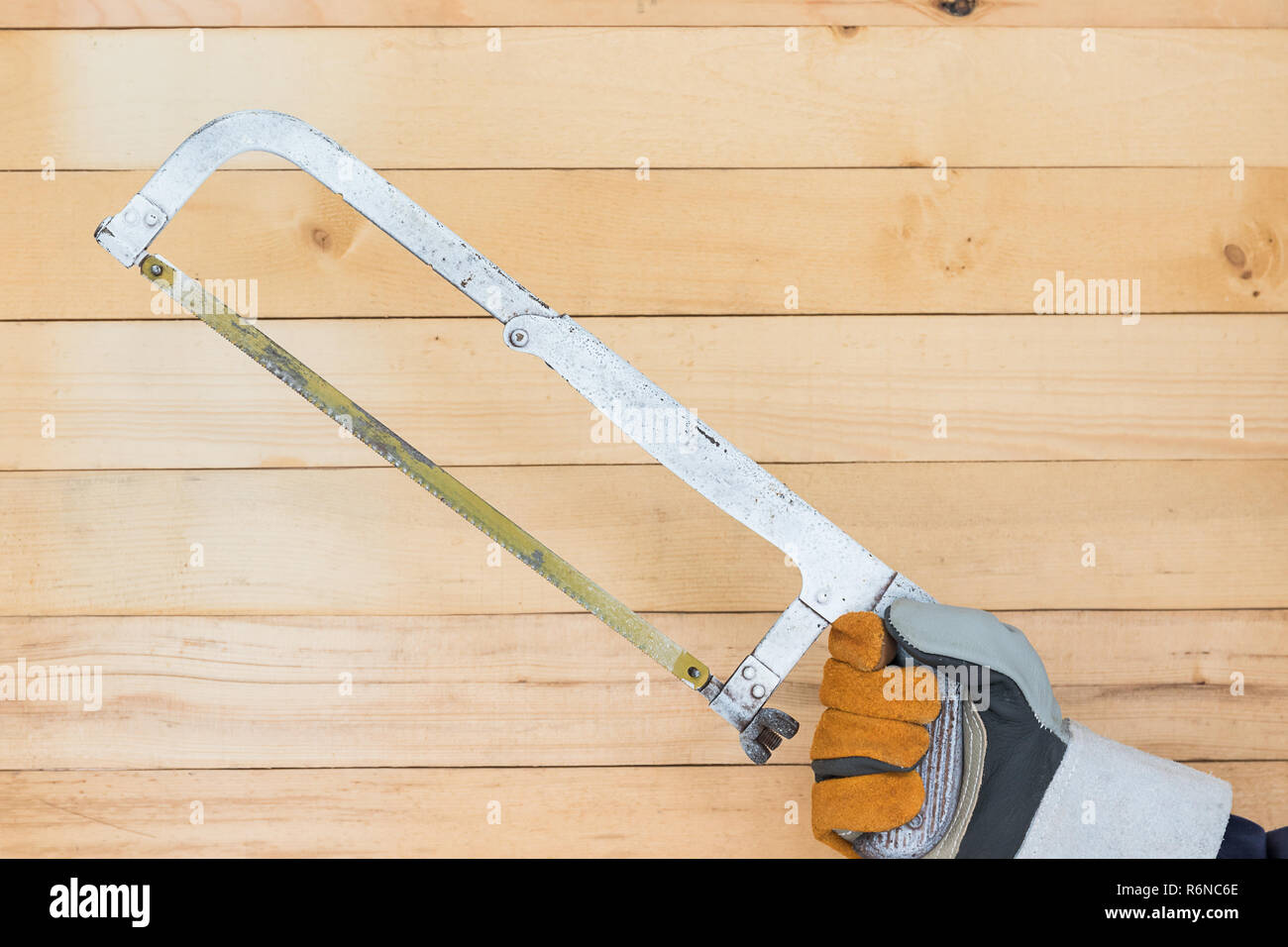 Hand in glove holding hack saw Stock Photo - Alamy