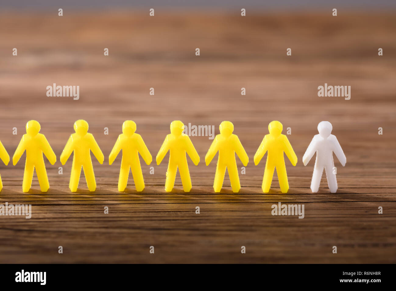 White Figure Standing Among Yellow Human Figures Stock Photo - Alamy