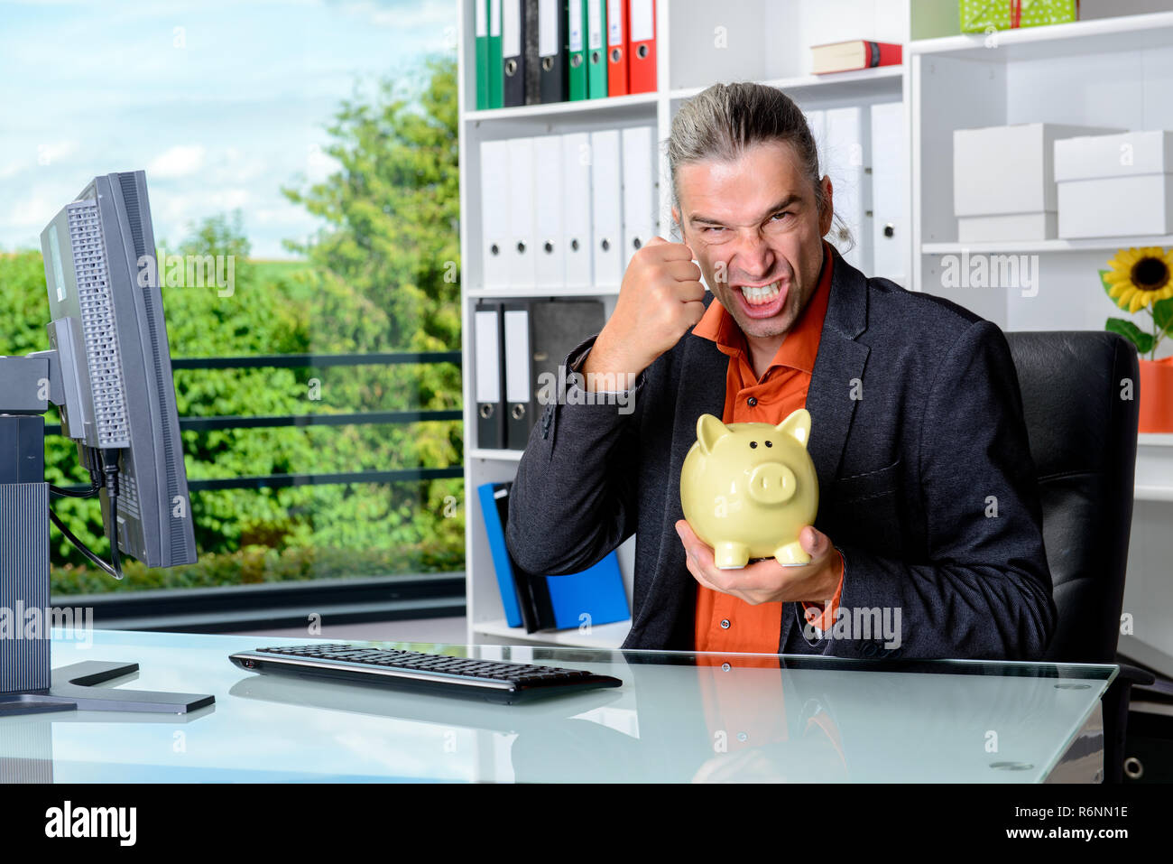 angry business man at his desk with piggy bank Stock Photo - Alamy