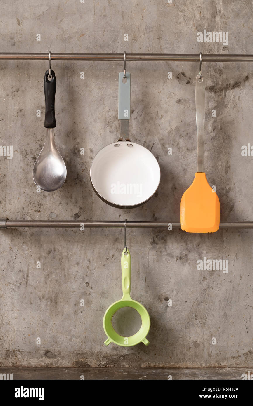 Kitchenware hanging on stainless rail on cement wall background Stock ...