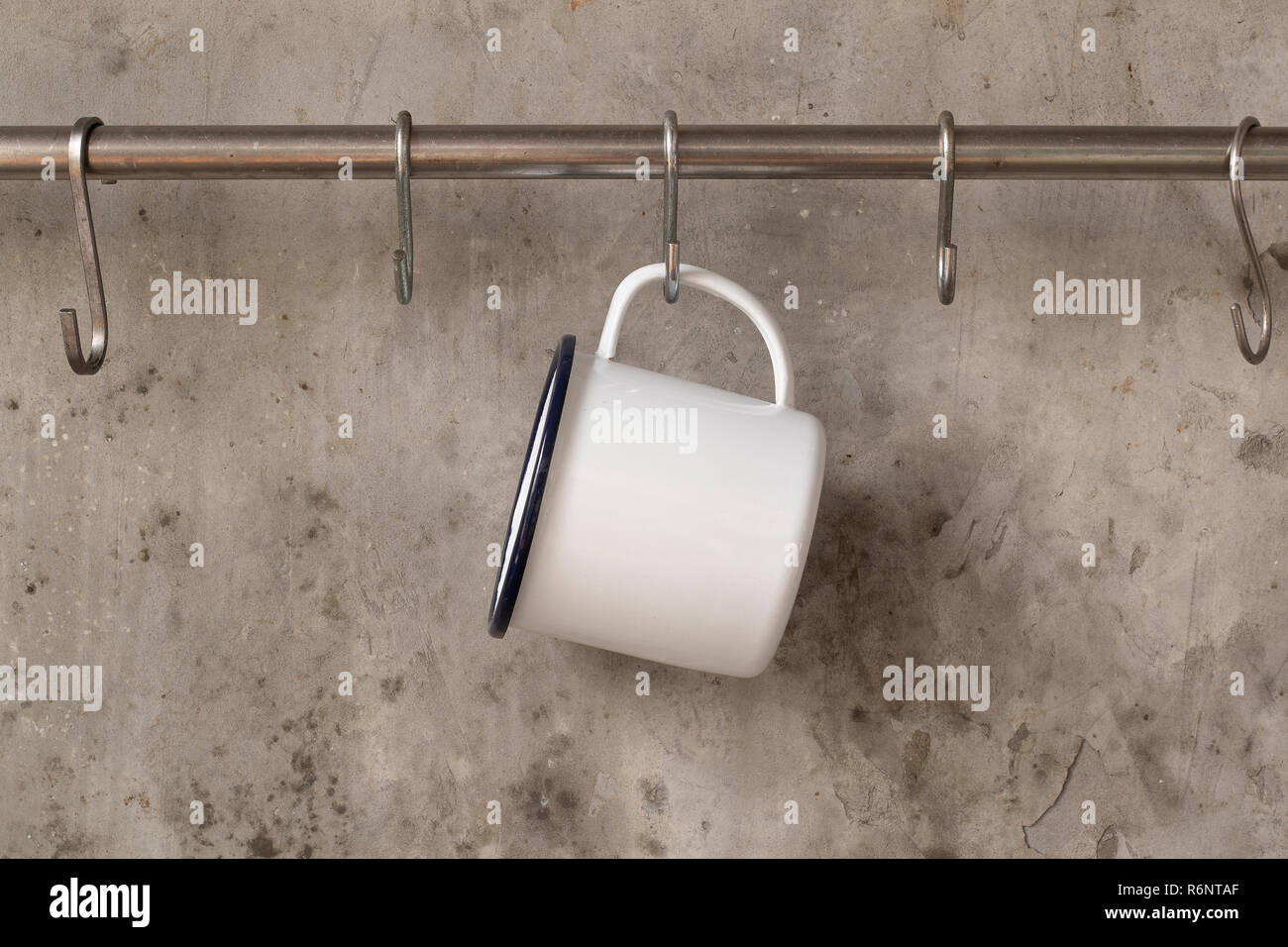 White tin cup hanging on stainless rail on cement wall background Stock ...