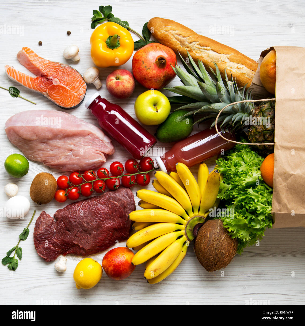 Full paper bag of healthy raw food on white wooden background. Cooking ...