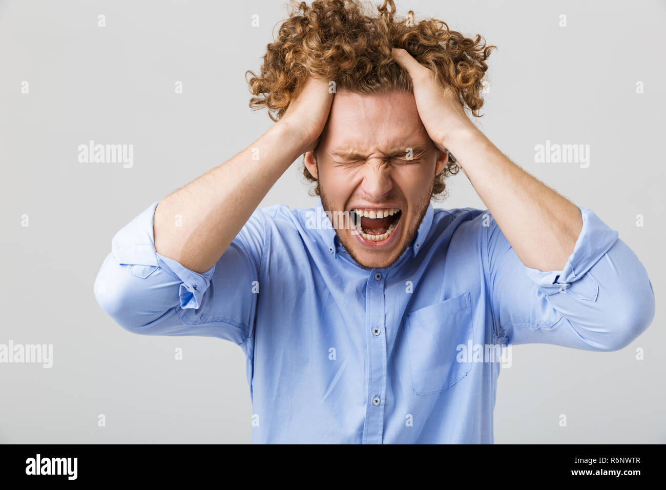 Portrait of a mad young man with curly hair isolated over white ...