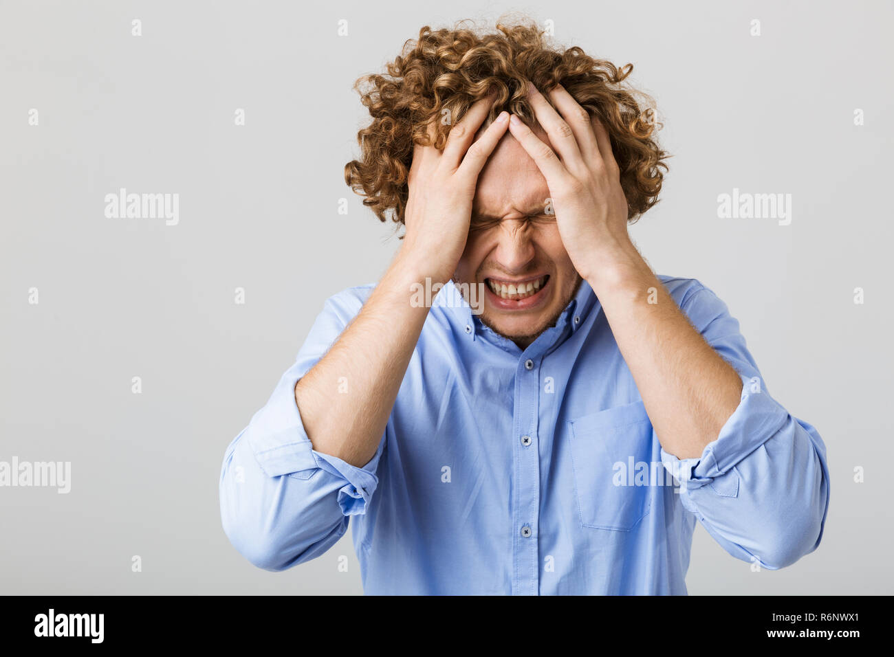 Portrait of a desperate young man wearing shirt standing isolated over ...