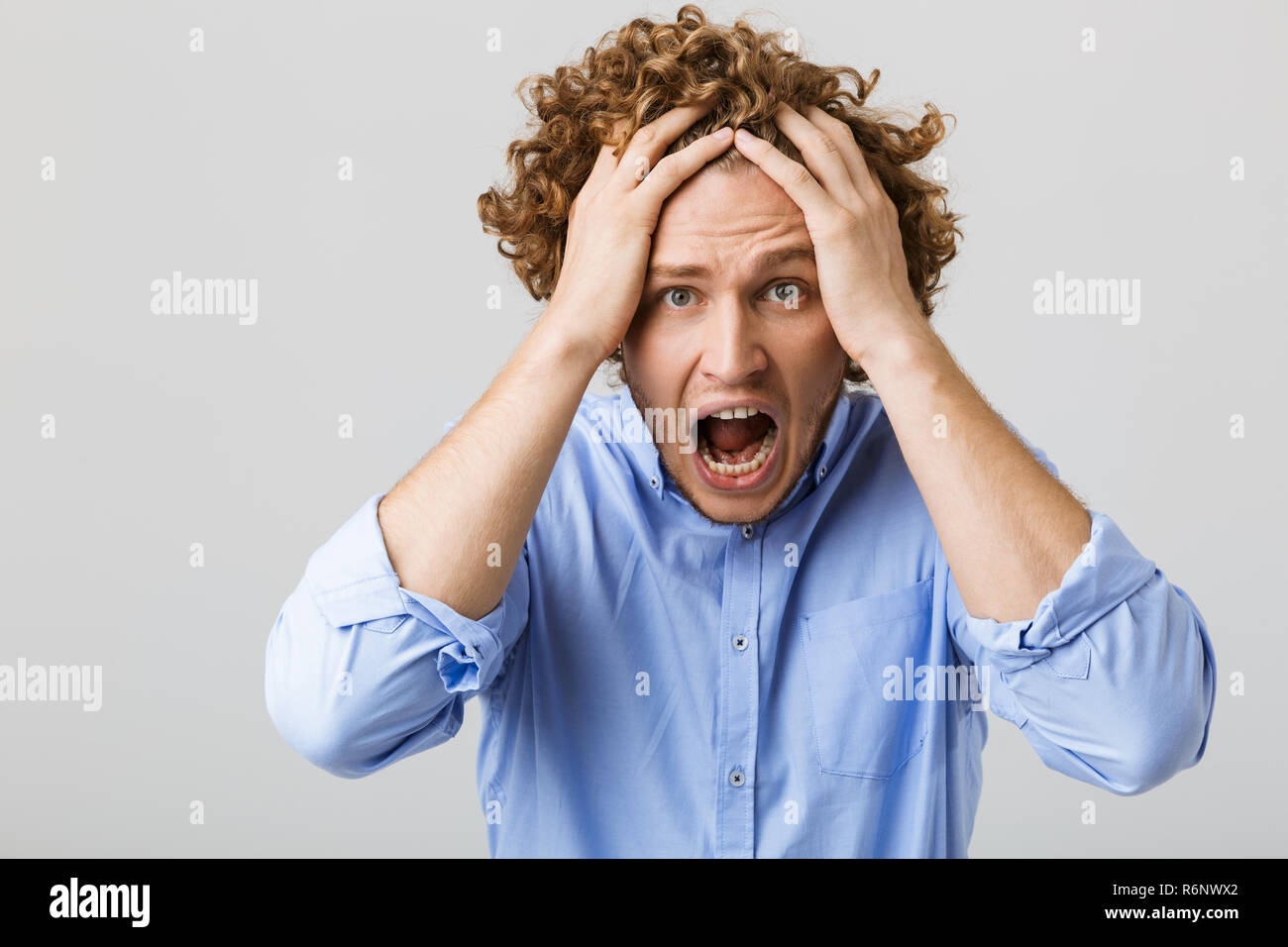 Portrait of a shocked young man wearing shirt standing isolated over ...