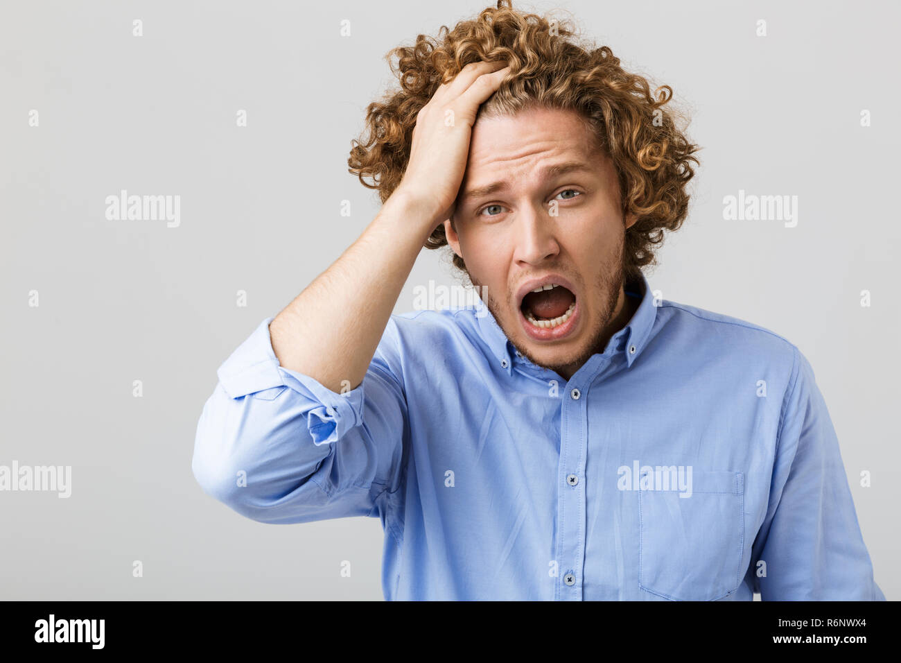 Portrait of a shocked young man wearing shirt standing isolated over ...