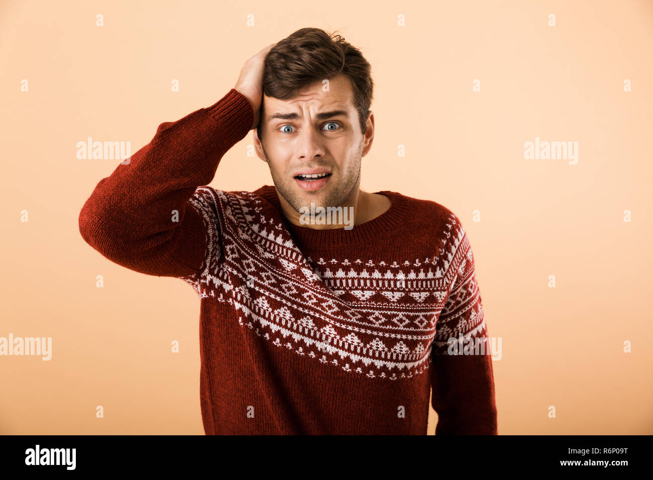 Image of uptight man 20s with stubble wearing knitted sweater grabbing ...