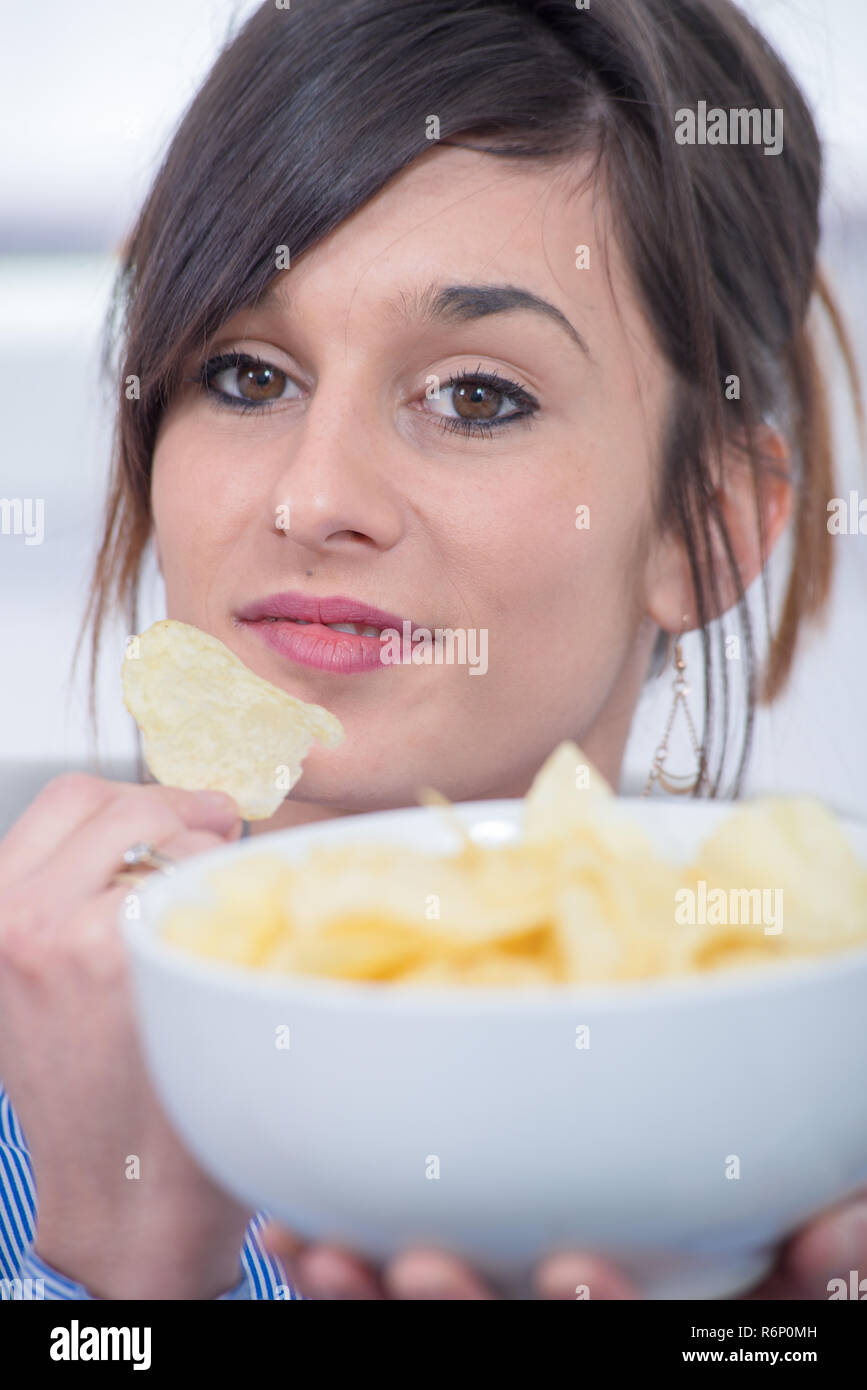 young brunette woman eating chips Stock Photo - Alamy