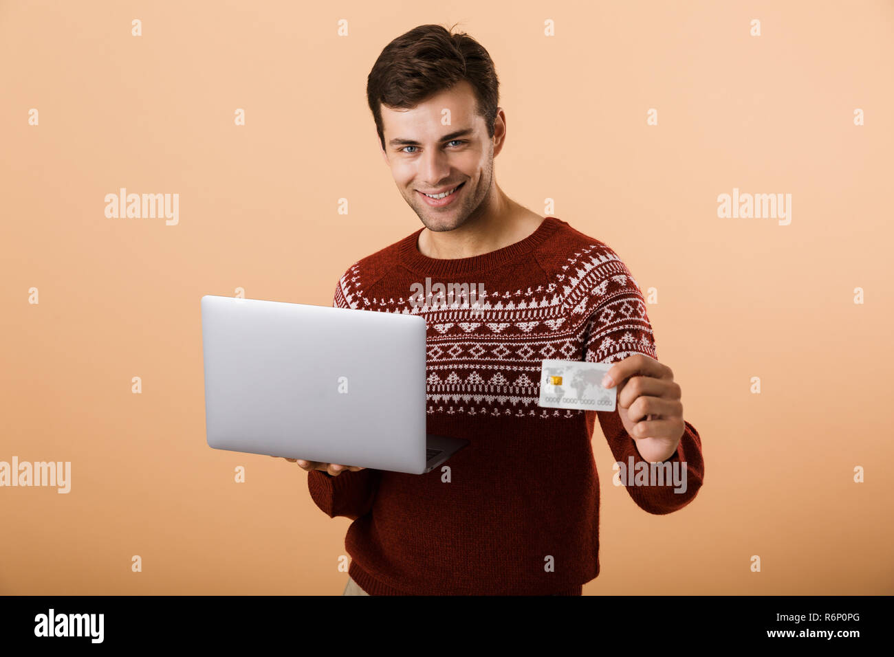 Portrait a cheerful young man dressed in sweater isolated over beige ...
