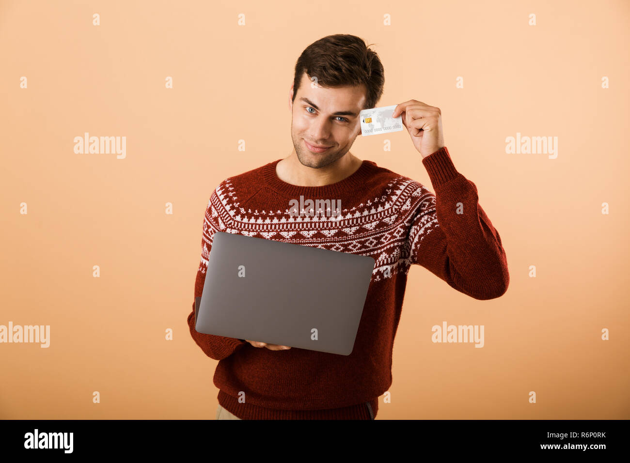 Portrait a handsome young man dressed in sweater isolated over beige ...