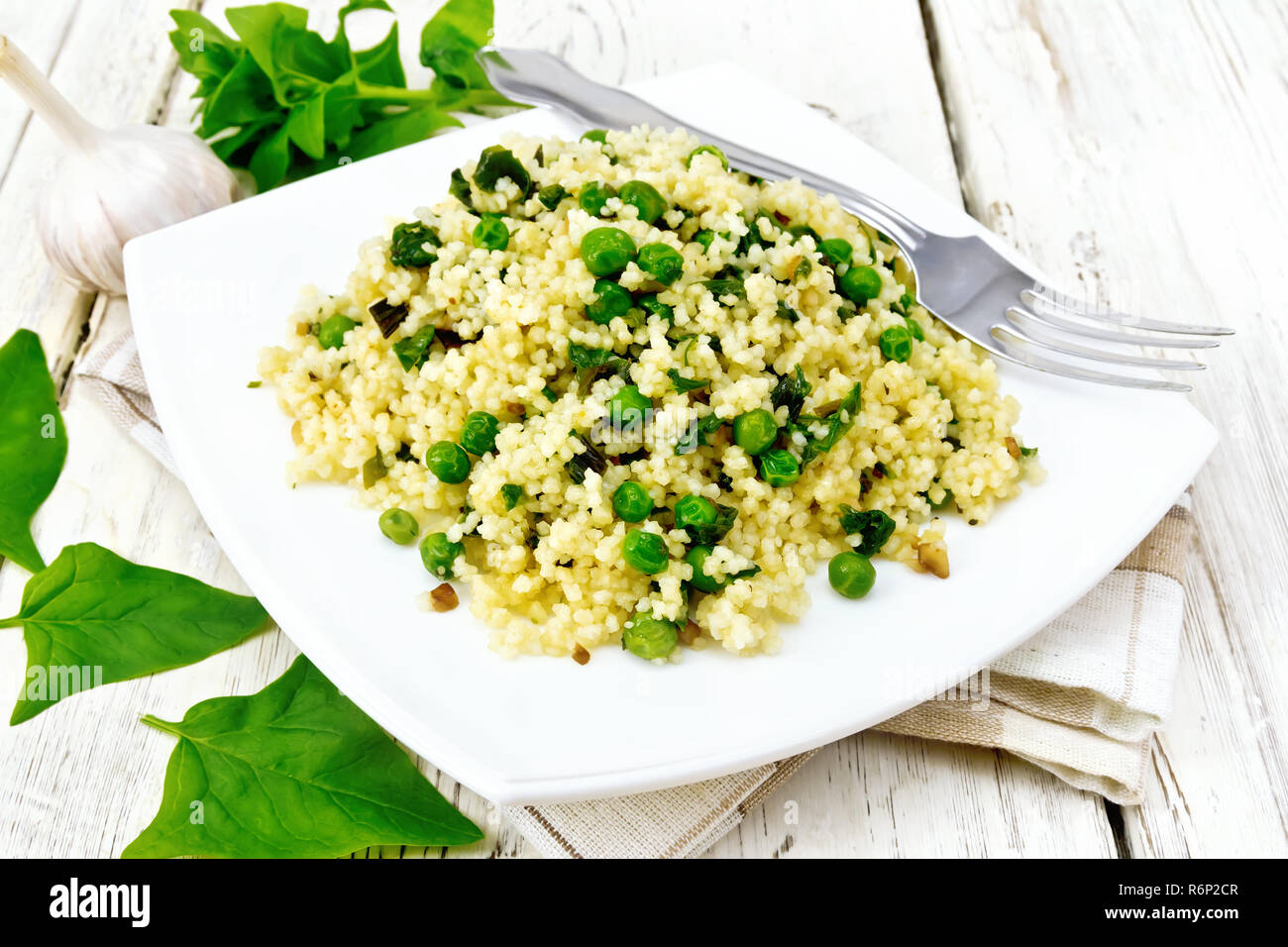 Couscous with spinach in plate on light board Stock Photo - Alamy