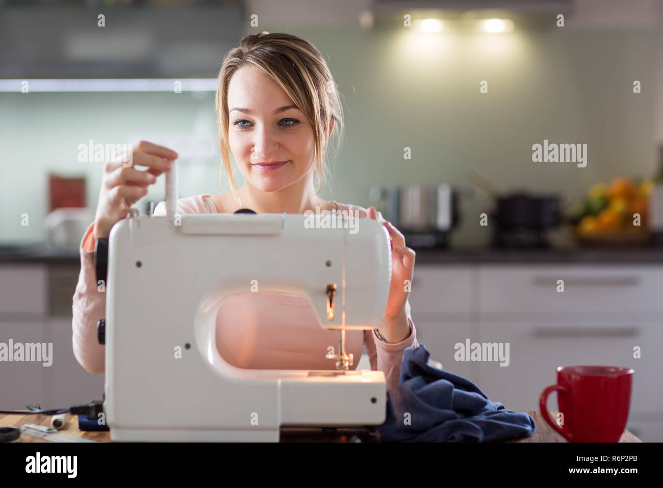 Beautiful young woman sewing clothes with sewing machine (color toned ...