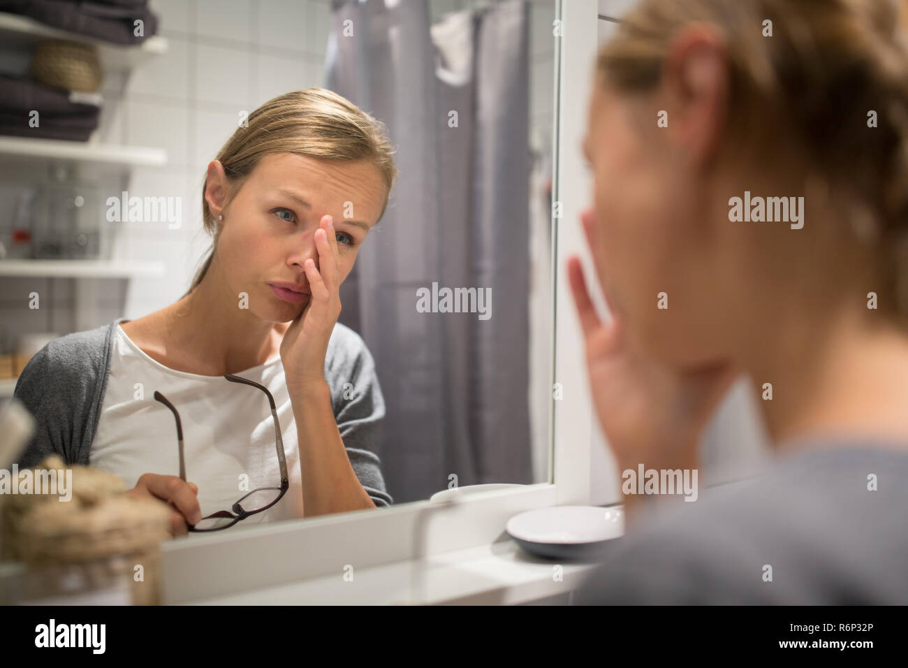 Groggy, young woman yawning in front of her bathroom mirror in the ...