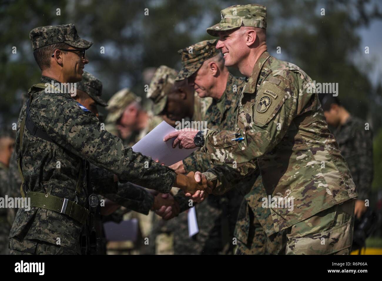 Command Sgt. Maj. Shawn Carns from Joint Task Force – Bravo hands a ...