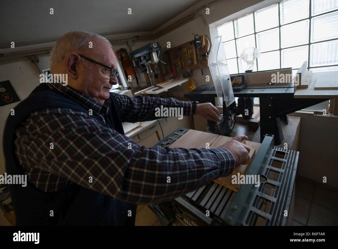 Retired Chief Master Sgt. Charles E. Milam cuts a piece of wood down ...
