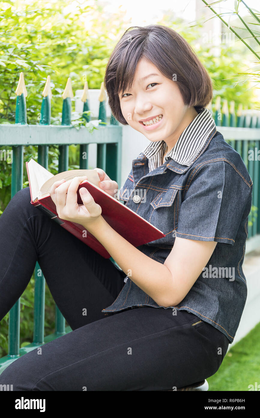 Woman reading book sitting on chair Stock Photo - Alamy