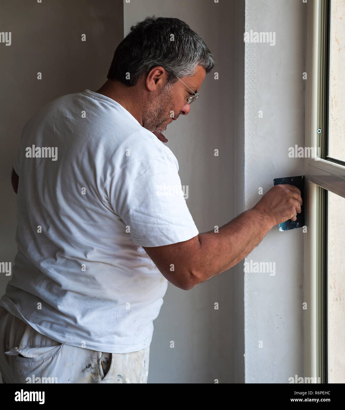 Worker using a putty knife, rear view. Focused Focus is on the tools ...