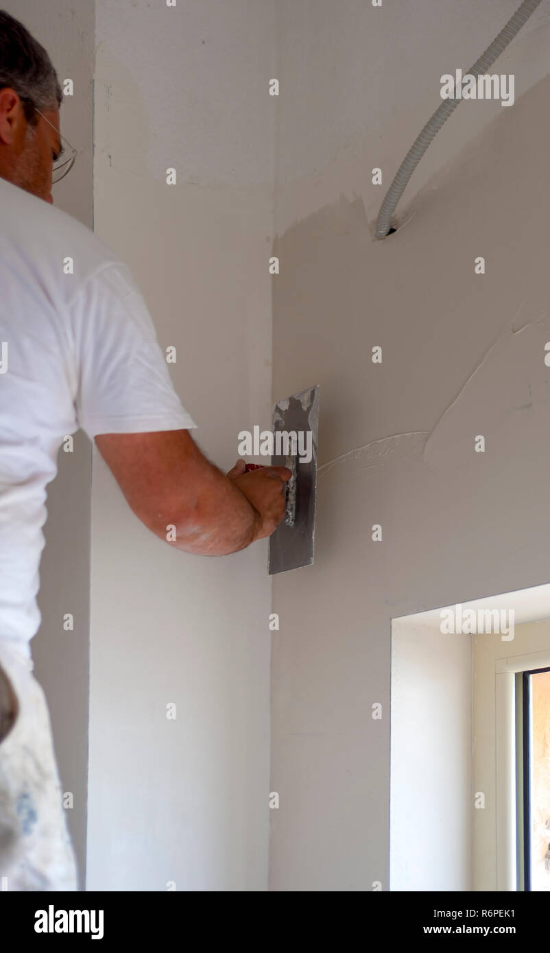 Worker using a putty knife, rear view. Focused Focus is on the tools ...