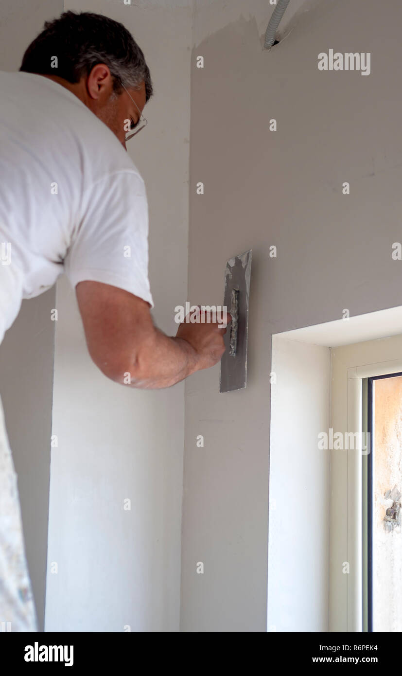 Worker using a putty knife, rear view. Focused Focus is on the tools ...