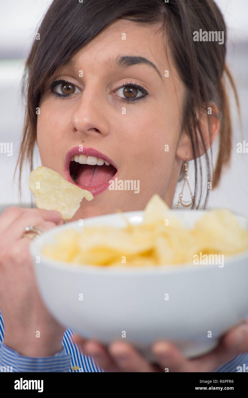 young brunette woman eating chips Stock Photo - Alamy