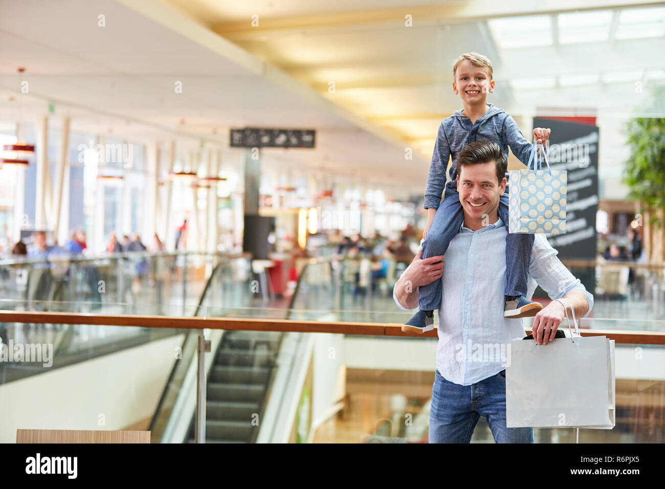 Father carries child on shoulders while shopping in a shopping center ...