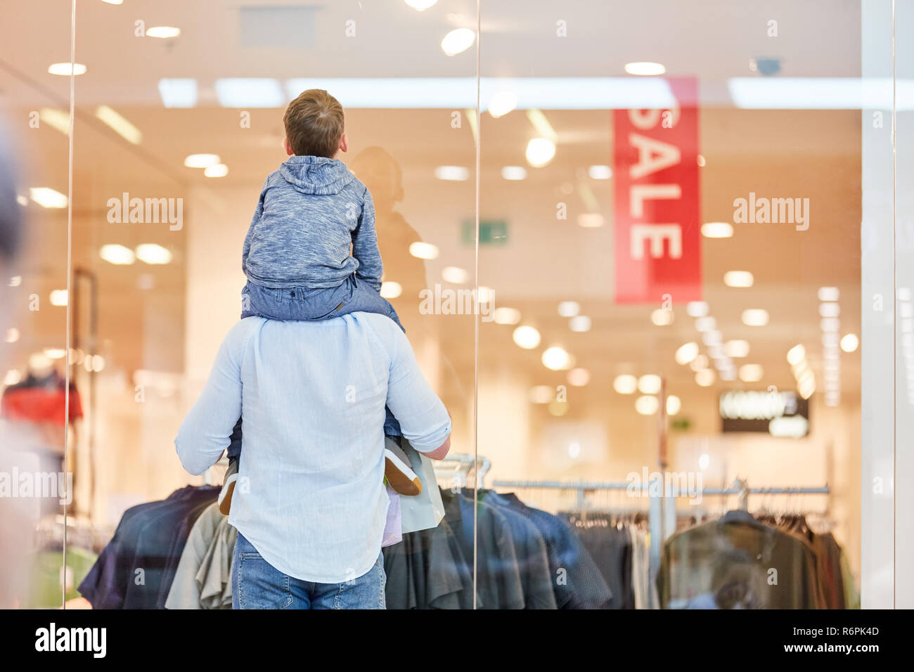 Man and child in front of a fashion store during sale in shopping mall ...