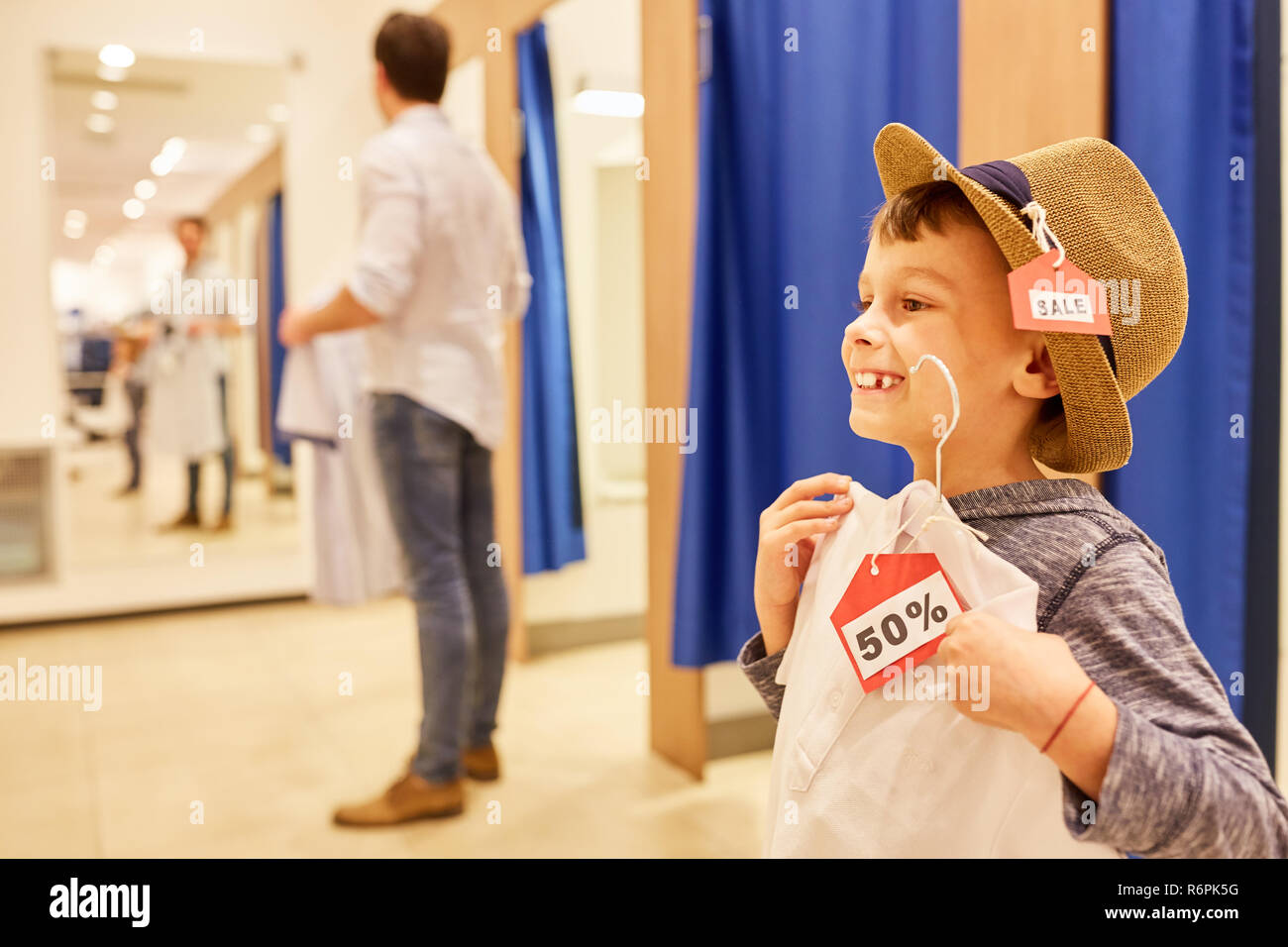 Boy trying on shirt and hat in fashion shop as a special offer on sale ...