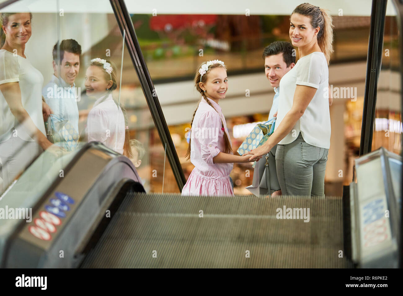 Family and children in the shopping center ride together escalator ...
