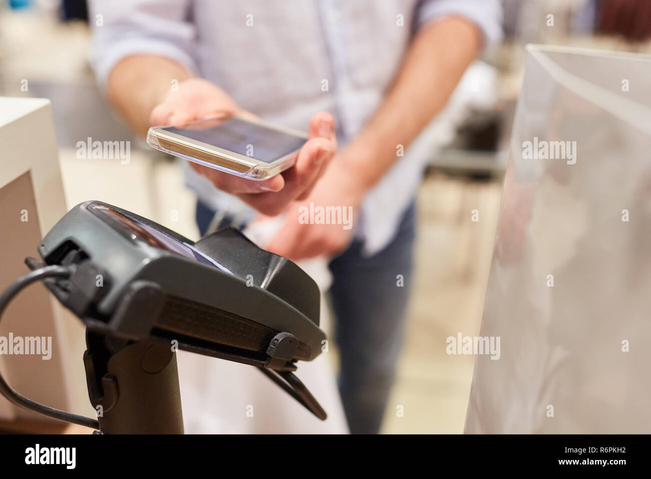 Customer pays with NFC smartphone at the card terminal in the shopping ...