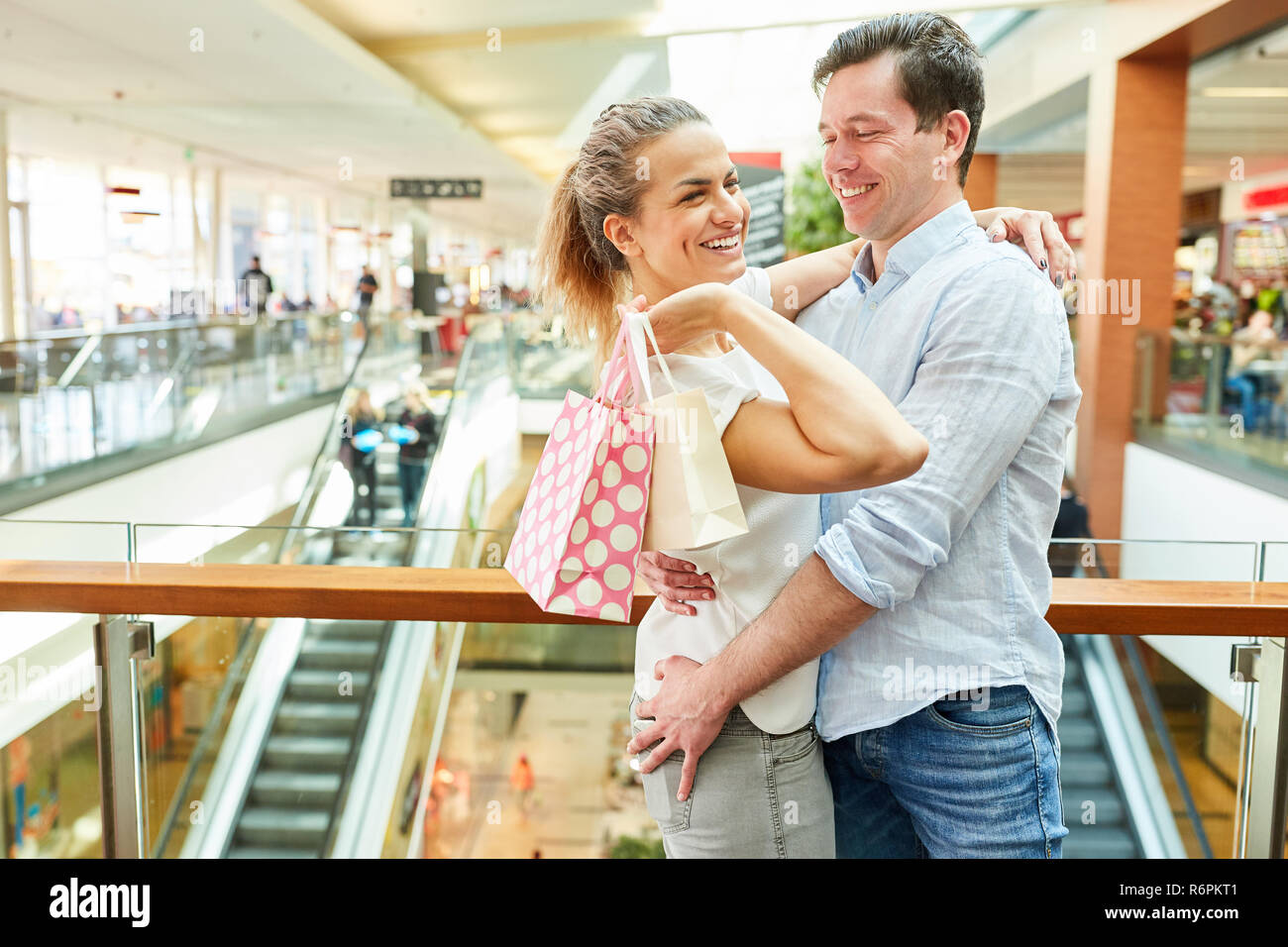 Happy young couple is having fun shopping together in shopping mall ...
