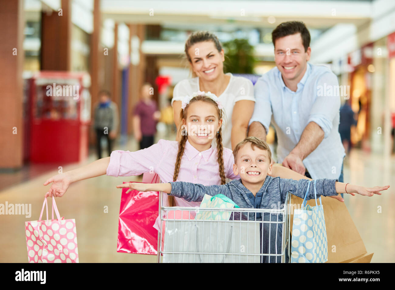 Cheerful parents and silly kids in shopping cart in shopping mall Stock ...