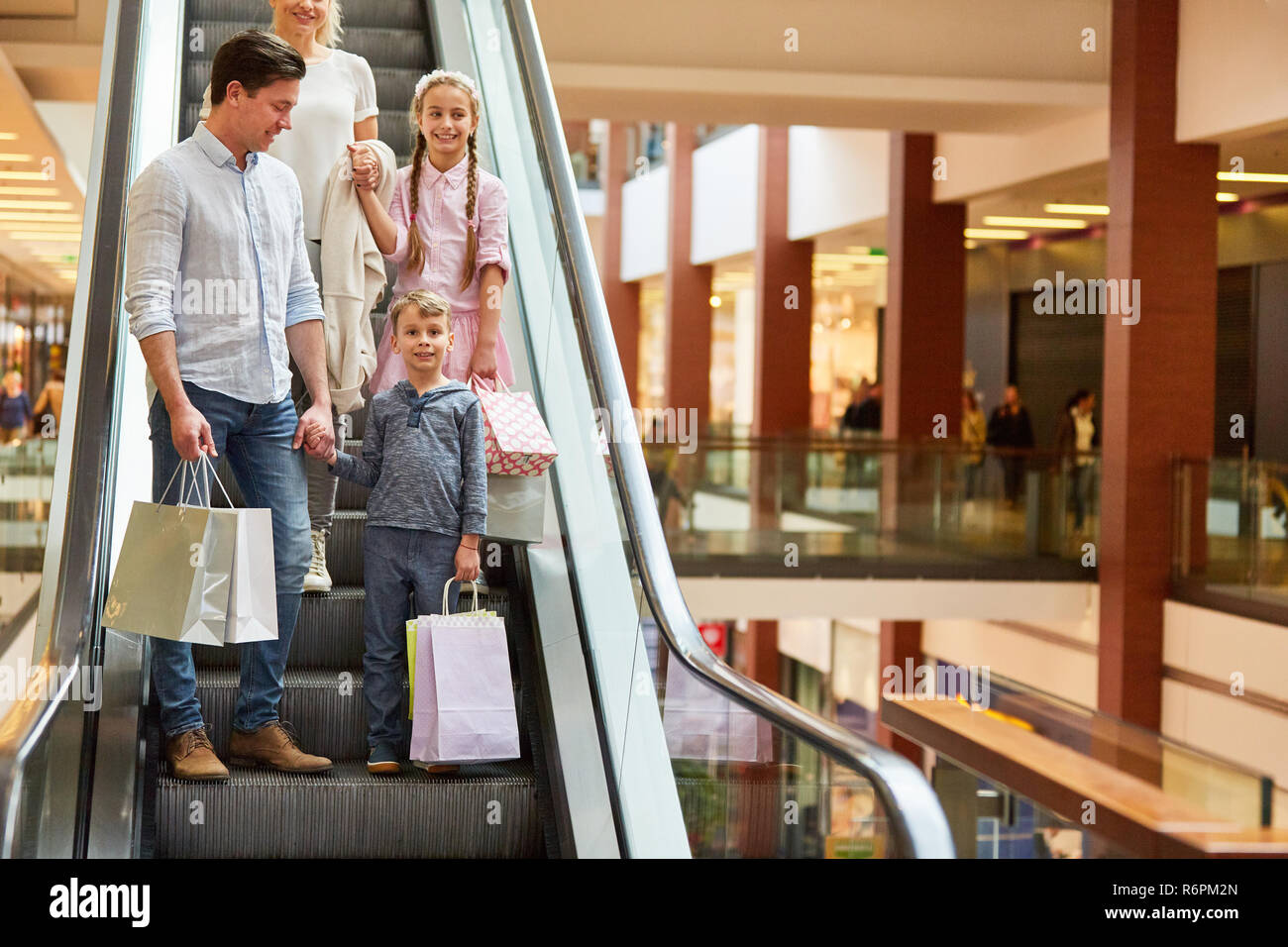 Family and two children ride on an escalator in the shopping center ...