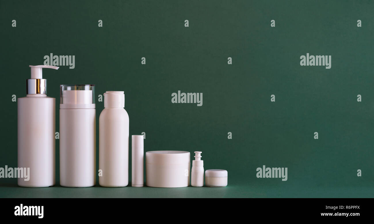 White cosmetic tubes on green background with copy space. Skin care ...