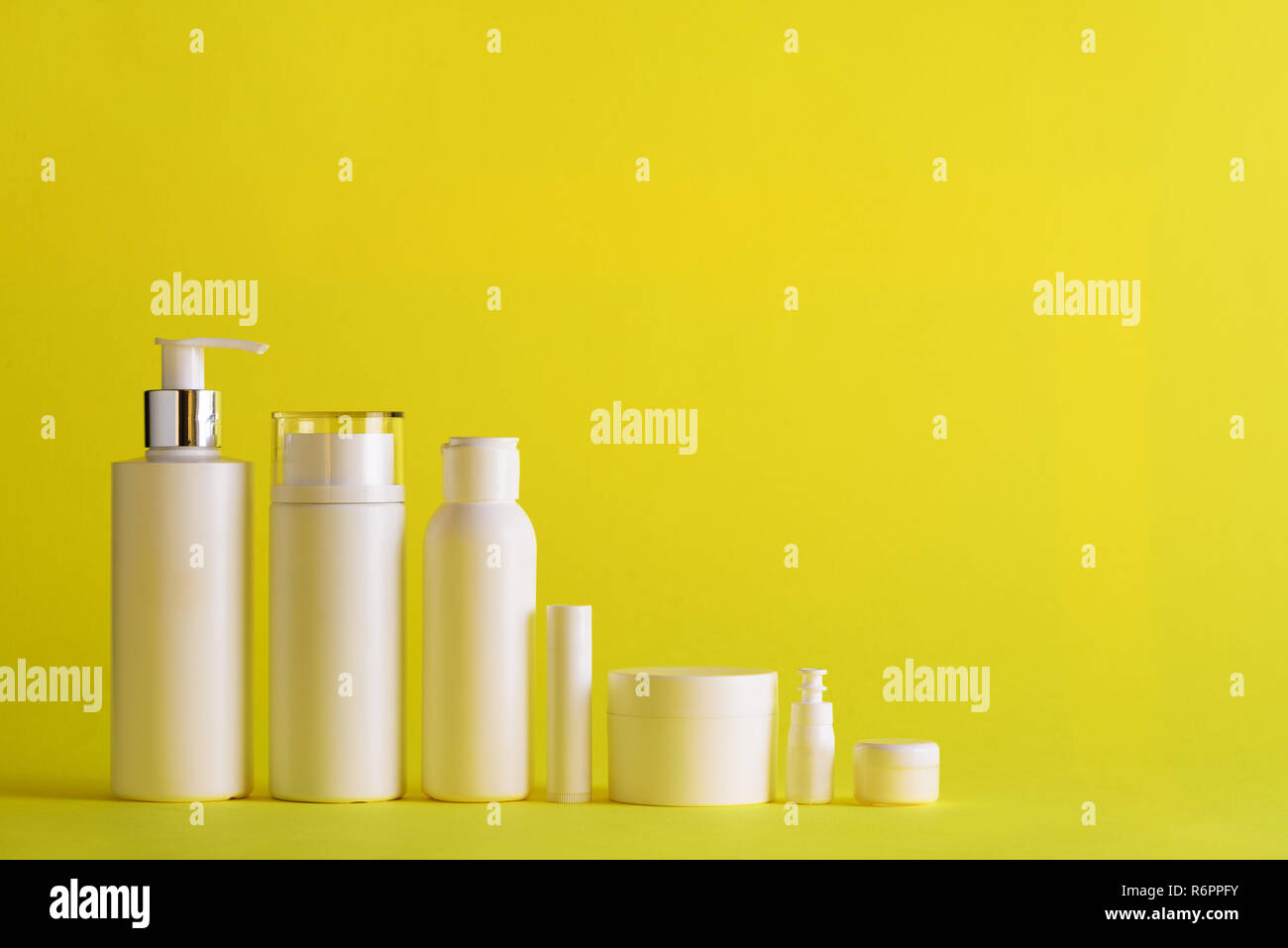 White cosmetic tubes on yellow background with copy space. Skin care ...