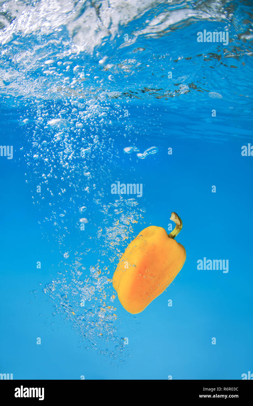 Bell pepper splashing in blue water Stock Photo - Alamy