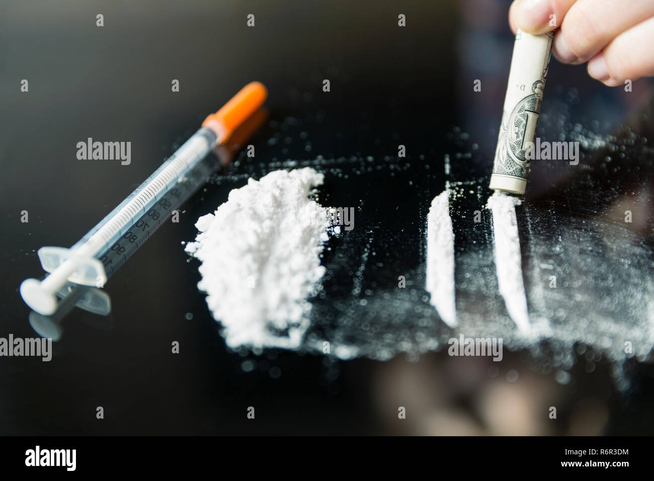 Cocaine divided into paths on a black background. Banknote and syringe ...
