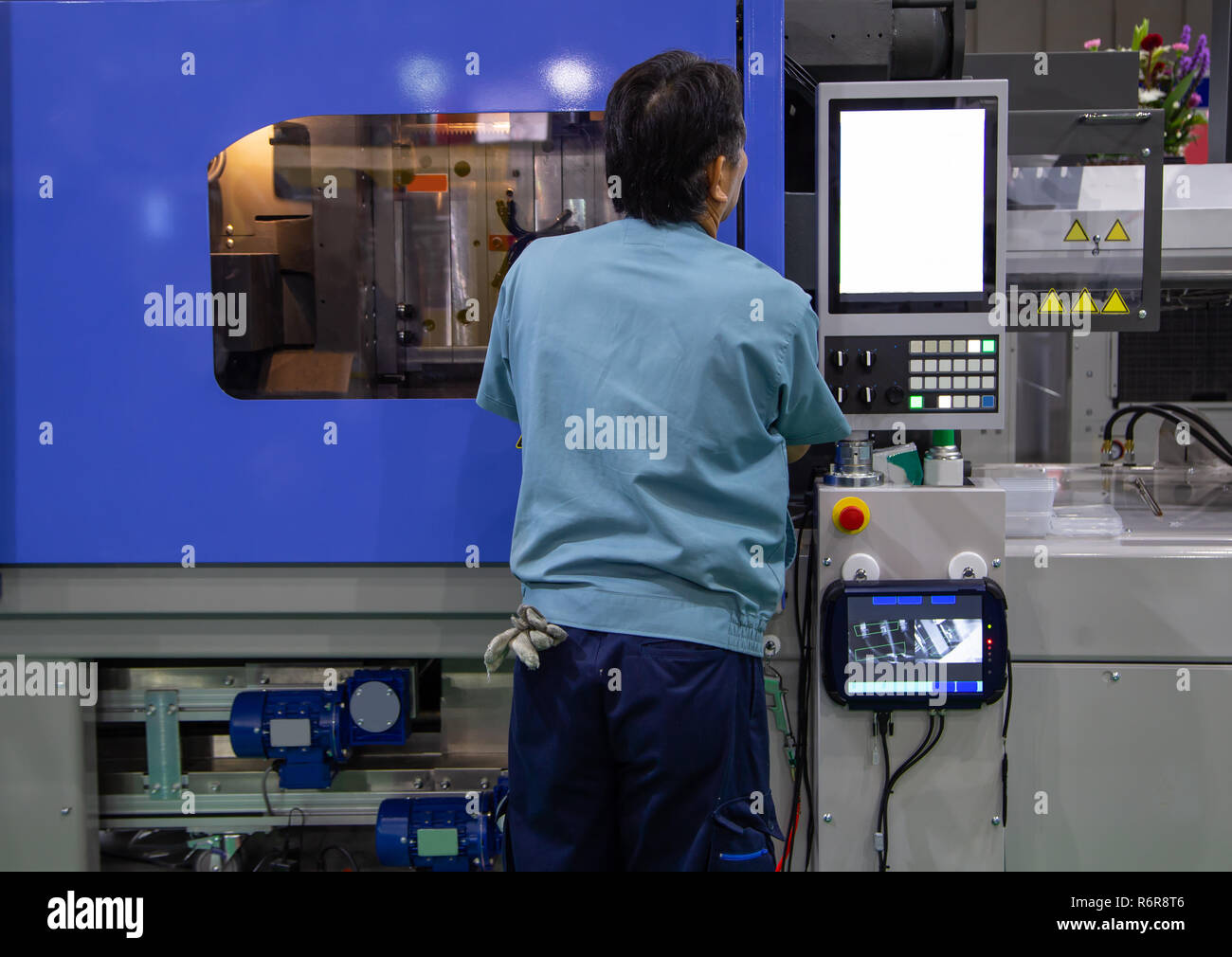 worker operate industrial plastic injection molding press machine for ...